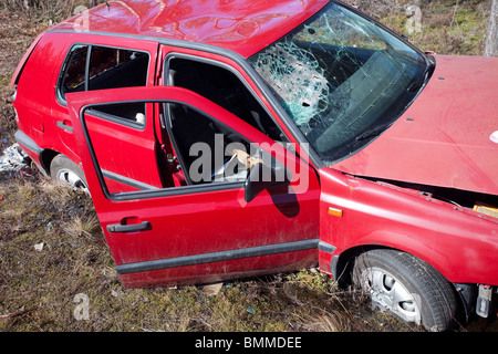 Crashed red VW Volkswagen Golf laying at roadside ditch at country road ...