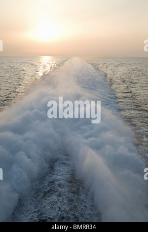 Foamy boat wake in the Pacific Ocean with island view at night in ...