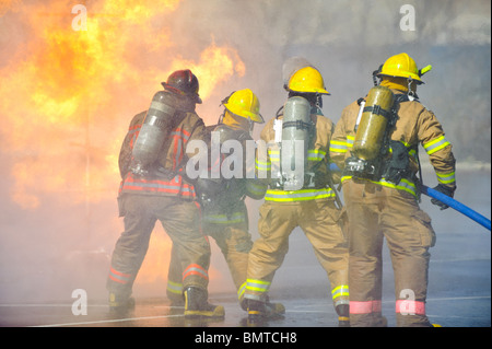 Directed by an officer in a red helmet, firefighters attack a propane ...