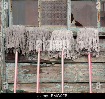 Four Chinese style mops are leaning against an old house so they can ...
