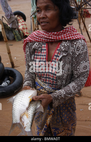 An old Khmer woman holds fish just caught in the Western Baray at ...