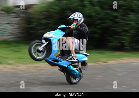 Teenager performs Wheelie on a blue moped .Both affordable and fun ...