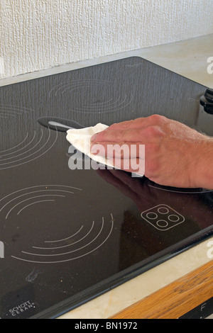 Man cleaning the cooker in the kitchen holding bottle with blank label ...