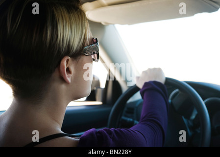 Woman driving an automobile, looking ahead and smiling while holding ...