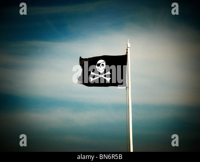 The Jolly Roger Skull and Swords Pirate flag on blue sky background ...