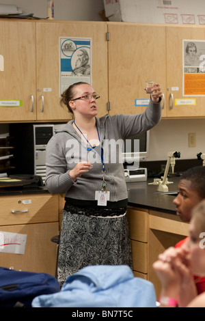 Anglo female high school science teacher explains experiment procedures ...