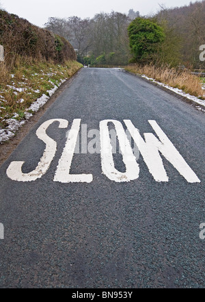 A SLOW sign on the brow of a hill on a road leading into the distance ...
