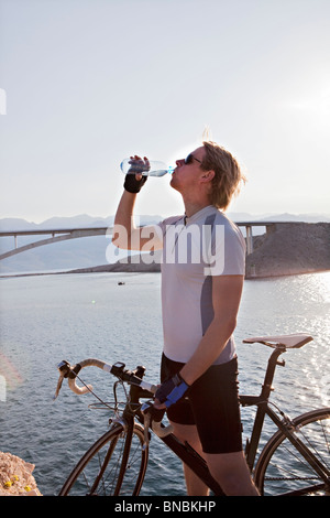 Cyclist drinking water while standing Stock Photo - Alamy