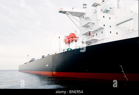 Oil tanker ship moored at marine terminal with fuel storage tanks and ...