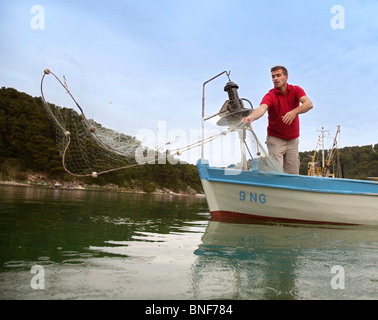 Young fisherman throwing a fishing net into the ocean Stock Photo - Alamy