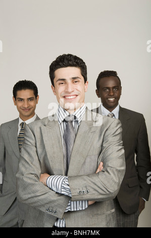 three cheerful multinational businessmen standing and using tablet in ...