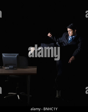 Angry businessman kicking computer monitor near stationery in office ...