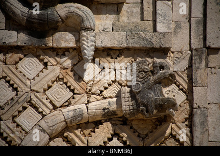 Mayan stone snake head sculpture with the pyramid of Kukulcan in the ...