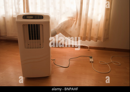 A portable air conditioning unit in use indoors showing the outlet pipe ...