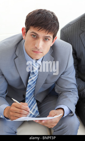 Businessman writing and sitting in a waiting room Stock Photo - Alamy
