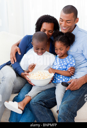 Family eating popcorn and watching TV in living room Stock Photo - Alamy