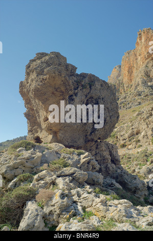 A large rock is on top of a hill. The rock is brown and has a pointed ...