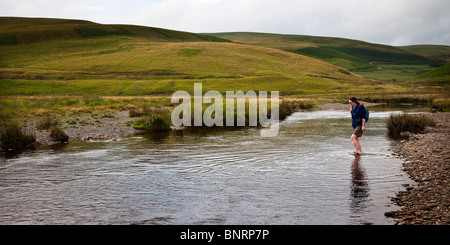 Female hiker crossing the Elan River on the Monks Trod ancient footpath ...