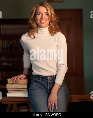 In the library - pretty female student with laptop and books working in ...