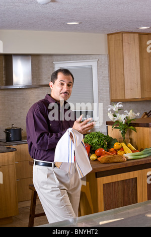Middle-aged man in kitchen stares at smartphone with pained face after ...