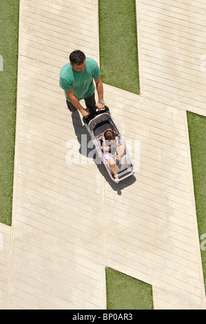Family walking father dad pushing babies twins in baby buggy on a ...