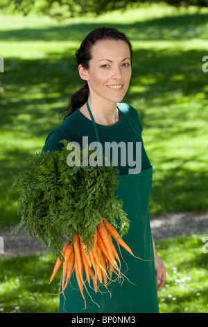 Portrait happy female gardener posing greenhouse surrounded by fresh ...