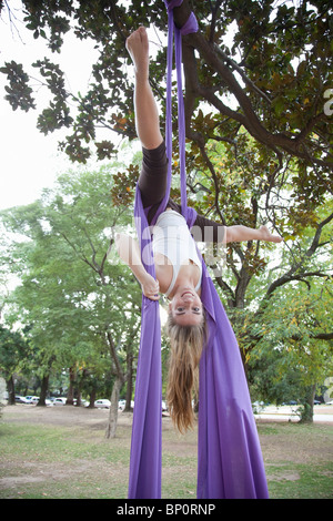 Young, smiling acrobat, with long hair, in a gray suit and leggings ...