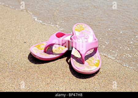 Summer slippers on the beach near the water. Sea shells on a sunny day ...