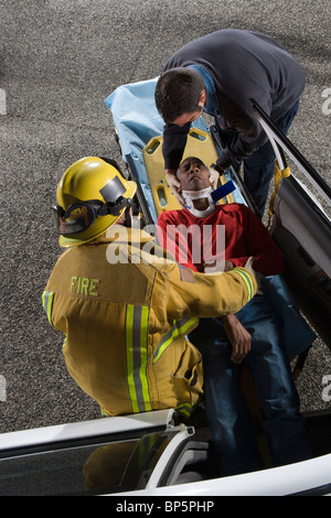 Firefighter and paramedic rescuing car accident victim Stock Photo - Alamy