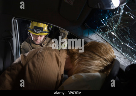 Firefighter rescuing car accident victim Stock Photo - Alamy