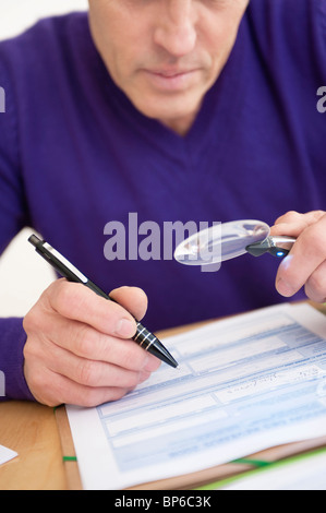 selective focus of man holding magnifying glass near coins on plaid ...