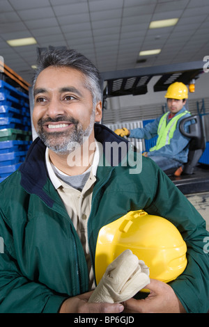 Cheerful man in high visibility vest and gloves talking to multiethnic ...