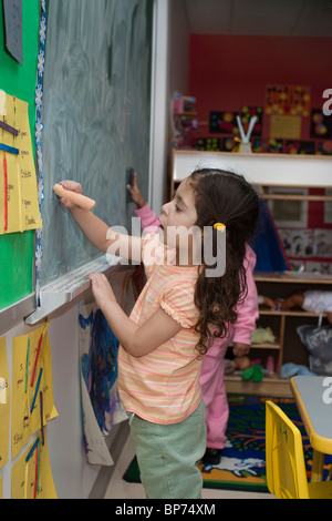 4 year old preschool girl writing on the blackboard at school Stock ...