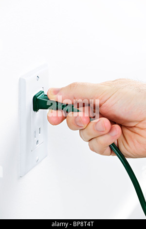Hand pulling green electrical plug from outlet Stock Photo - Alamy