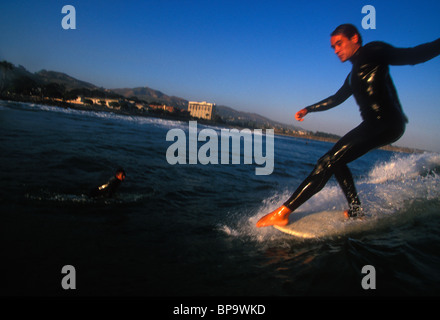 Male surfer hangs five surfing at sunset, C-Street Ventura, California ...