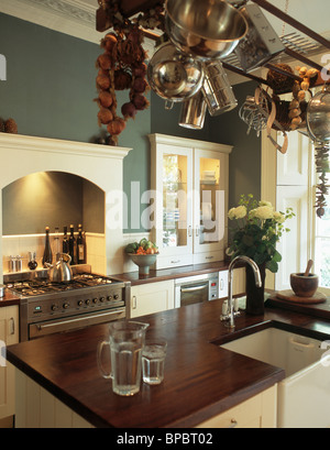 Pans on rack above island unit with storage baskets on shelves in cream ...