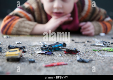 Boy in background of smashed toy cars. Shallow depth of field / select ...