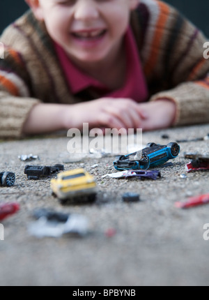 Boy in background of smashed toy cars. Shallow depth of field / select ...