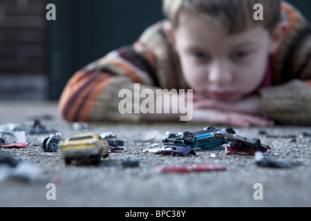 Boy in background of smashed toy cars. Shallow depth of field / select ...