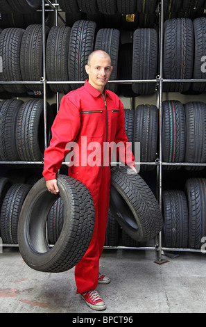 A motivated worker in a tire workshop carrying two tires Stock Photo ...