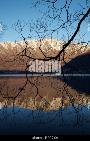 mountain lake in winter with calm open water and mountain wall behind ...
