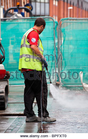 A man using a high pressure power wash to clean the white granite and ...