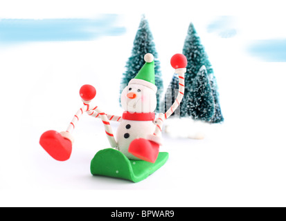 Snowman christmas character sliding down a snowhill on a sled with pine ...