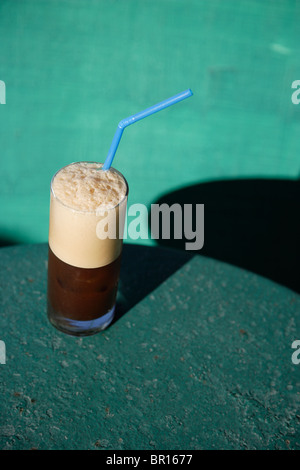 A vertical closeup of a refreshing iced coffee in a glass next to ...