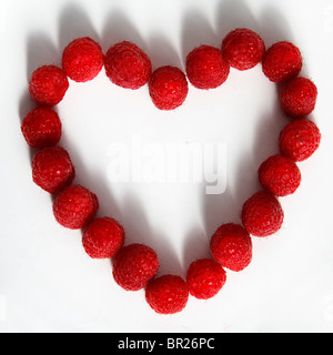 Fresh raspberries in heart shaped bowl with rose and green leaves on ...