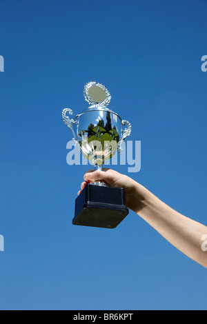 Human hand holding a silver trophy Stock Photo - Alamy
