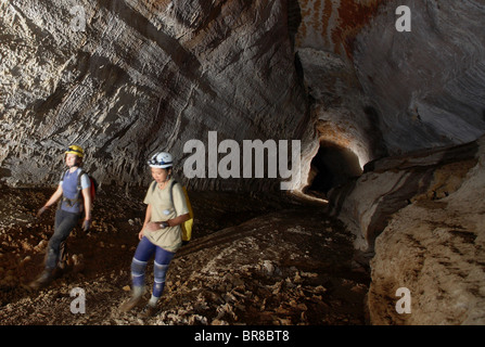 Two female cave explorers walk easily through a satisfying tunnel ...