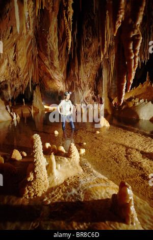 Cave explorer poses for a photograph in a well formed passage ...