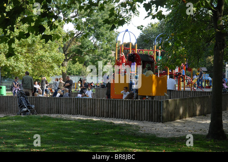 Parents and children playing on swings in Priory Park playground in ...