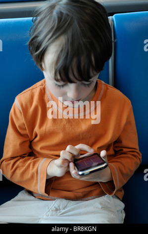little boy using an iphone while waiting for flight to spain Stock ...